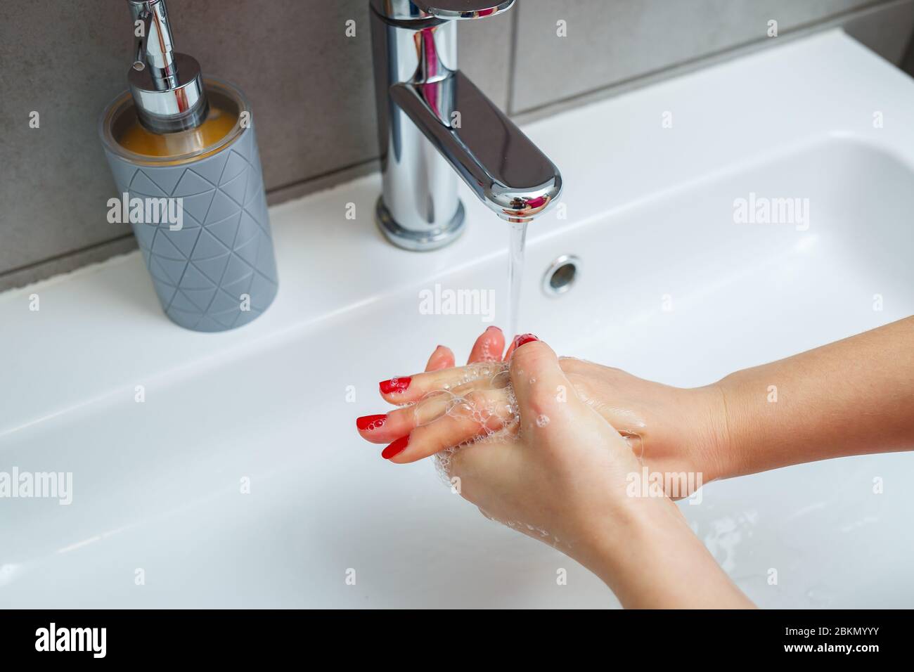 White sink with a silver faucet in the bathroom. Gray can with liquid ...