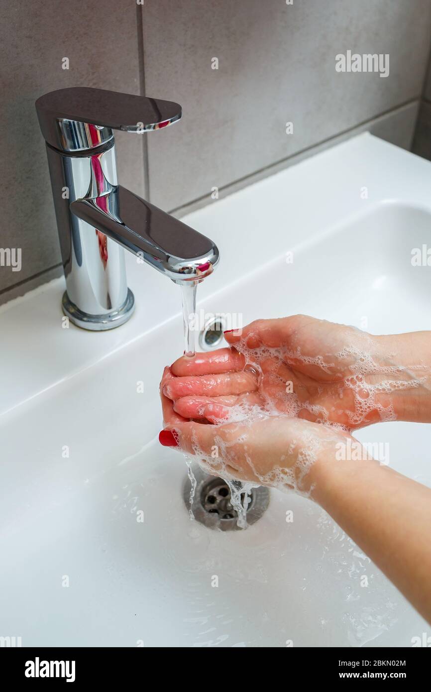 White sink with a silver faucet in the bathroom. Gray can with liquid ...