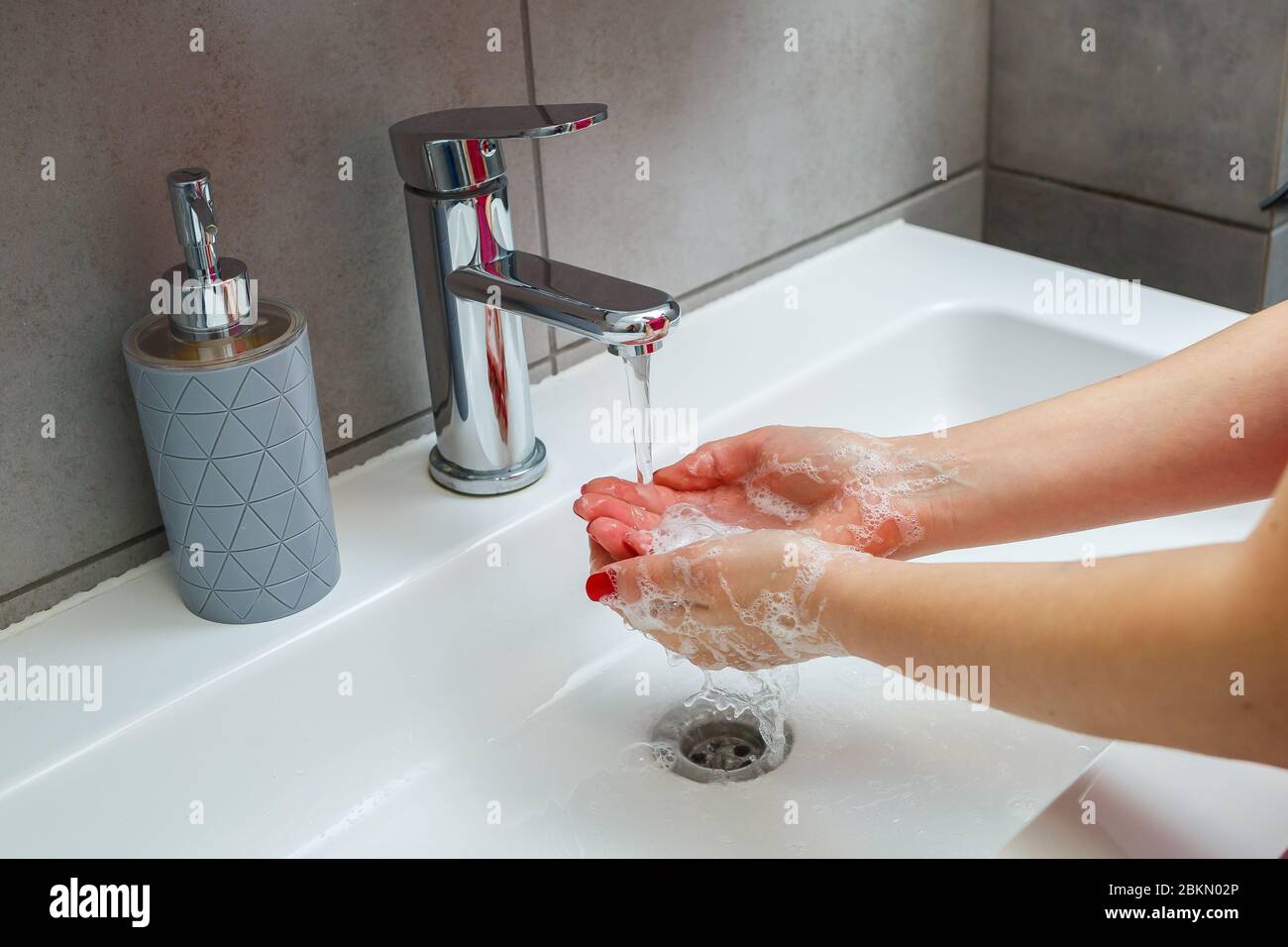 White sink with a silver faucet in the bathroom. Gray can with liquid ...