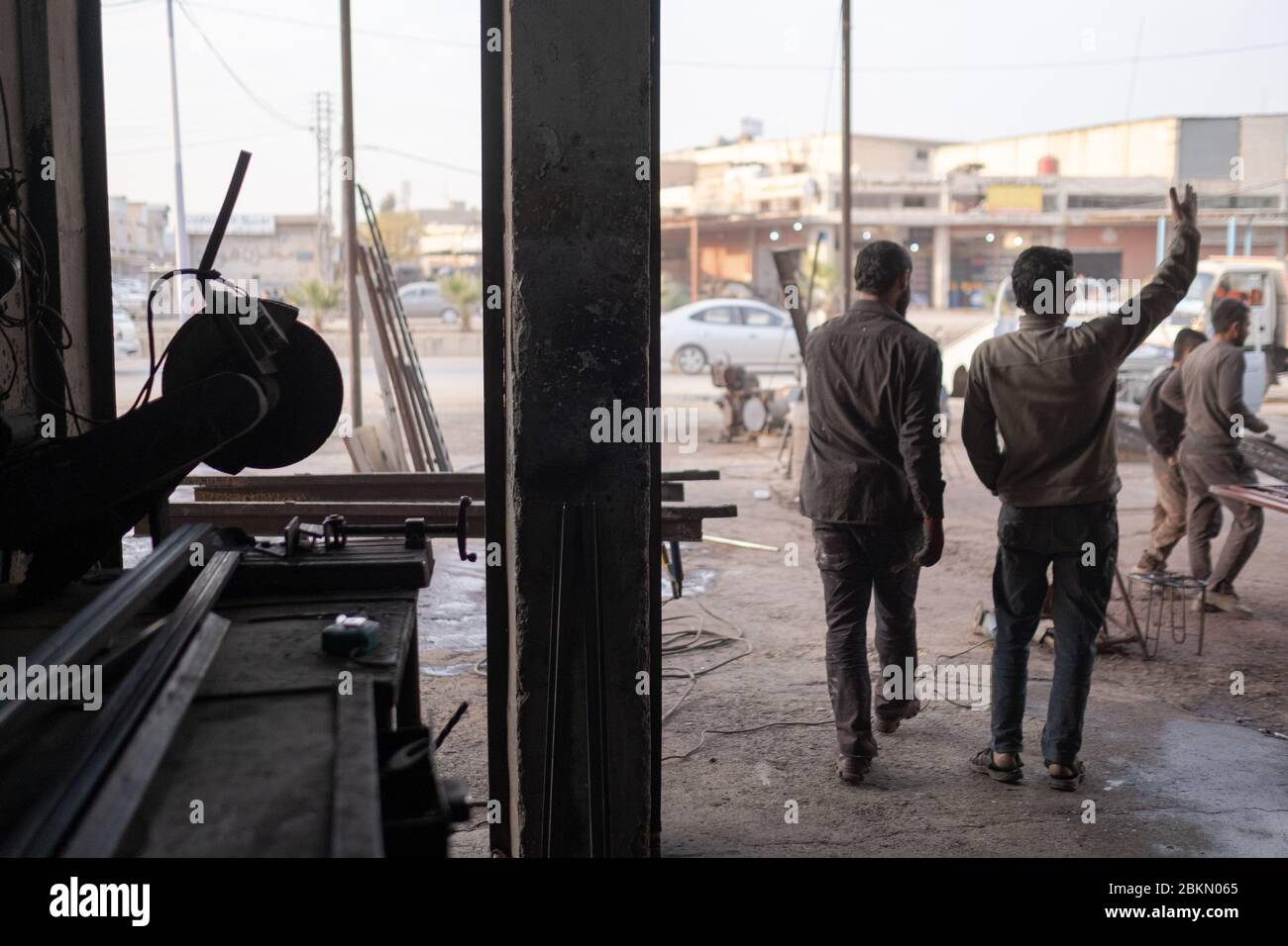 Workers take a break from metalwork in their workshop in Qamishli ...