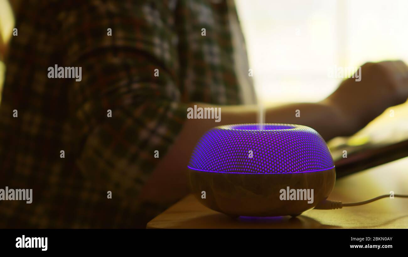 Mist from blue led electric essential oil diffuser while woman is ...