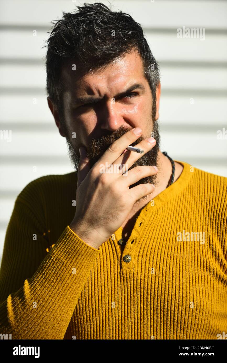 Smoker holds cigarette in mouth. Man with serious face on white stripy ...