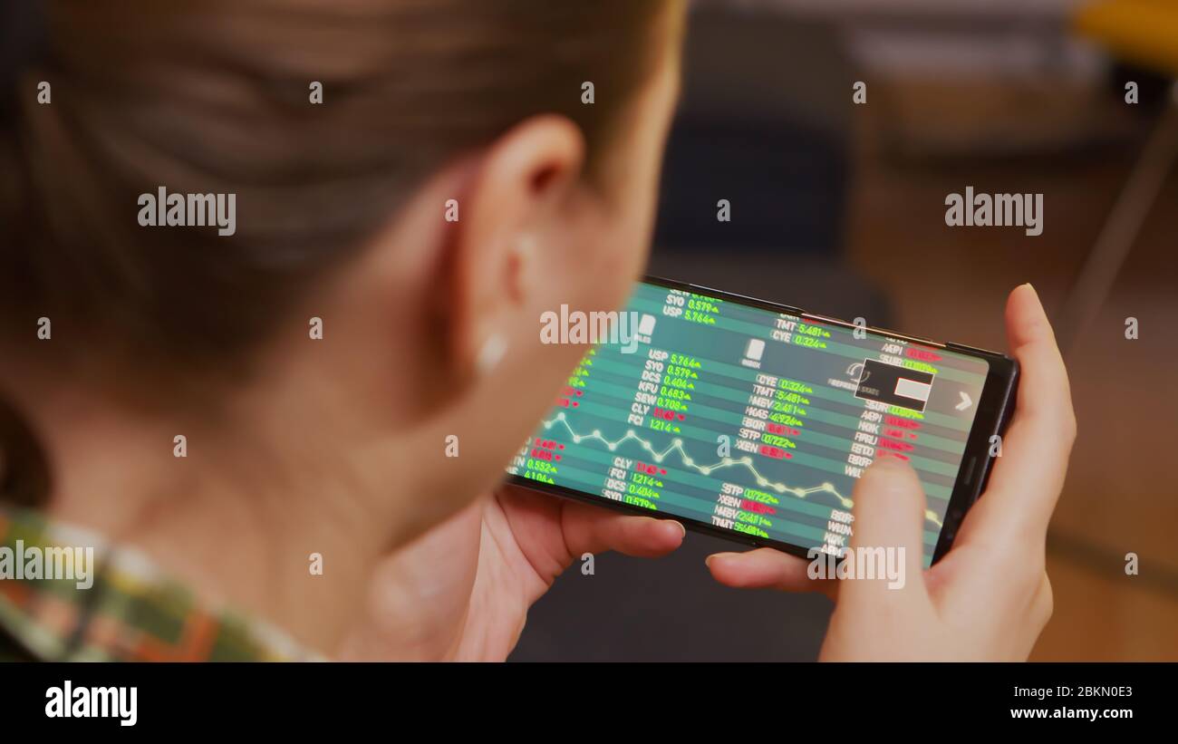 Back view of woman checking stock trading using smartphone Stock Photo ...