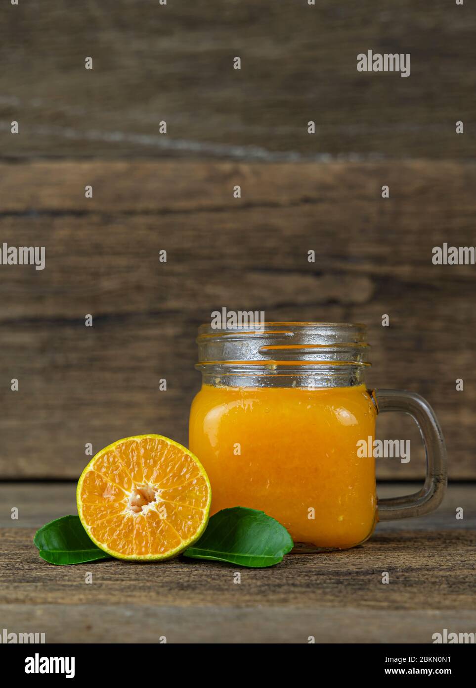Orange cut in half and a glass of orange juice on wooden table ...