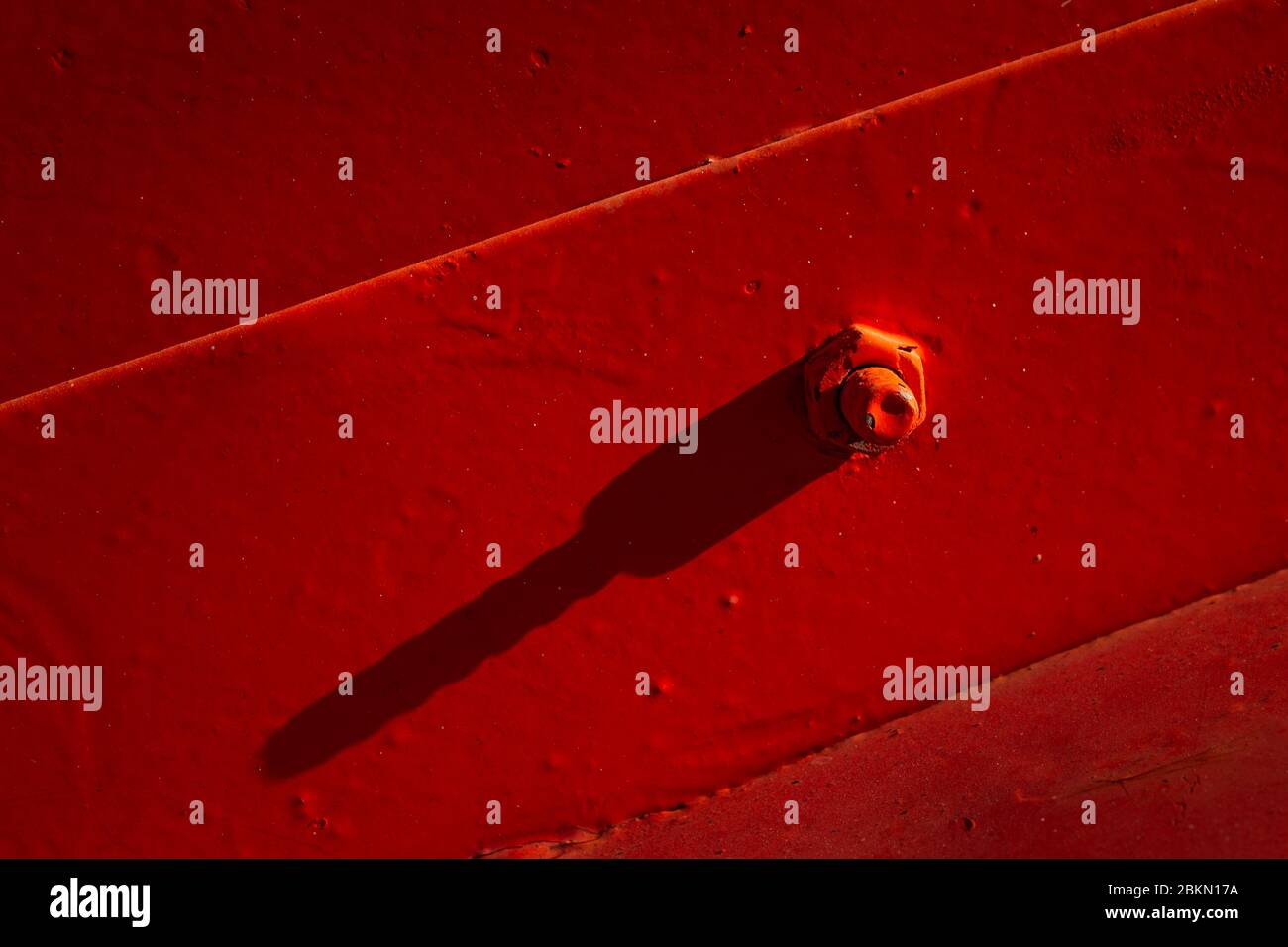 Old red painted nut and bolt on red metal wall with long shadows Stock ...