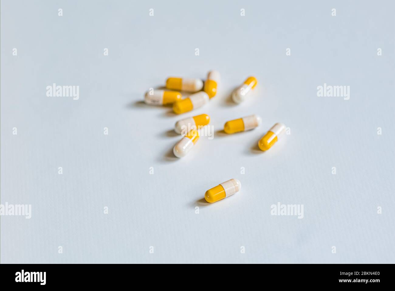 A small heap of yellow and white medical capsules, one capsule ...