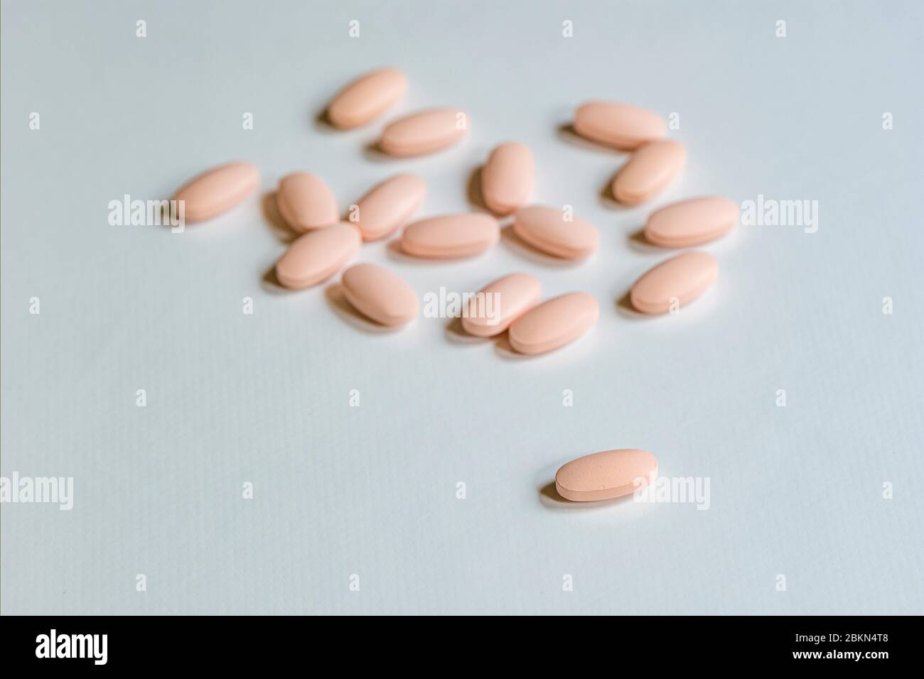 A small heap of light pink medical tablets, one tablet separated ...