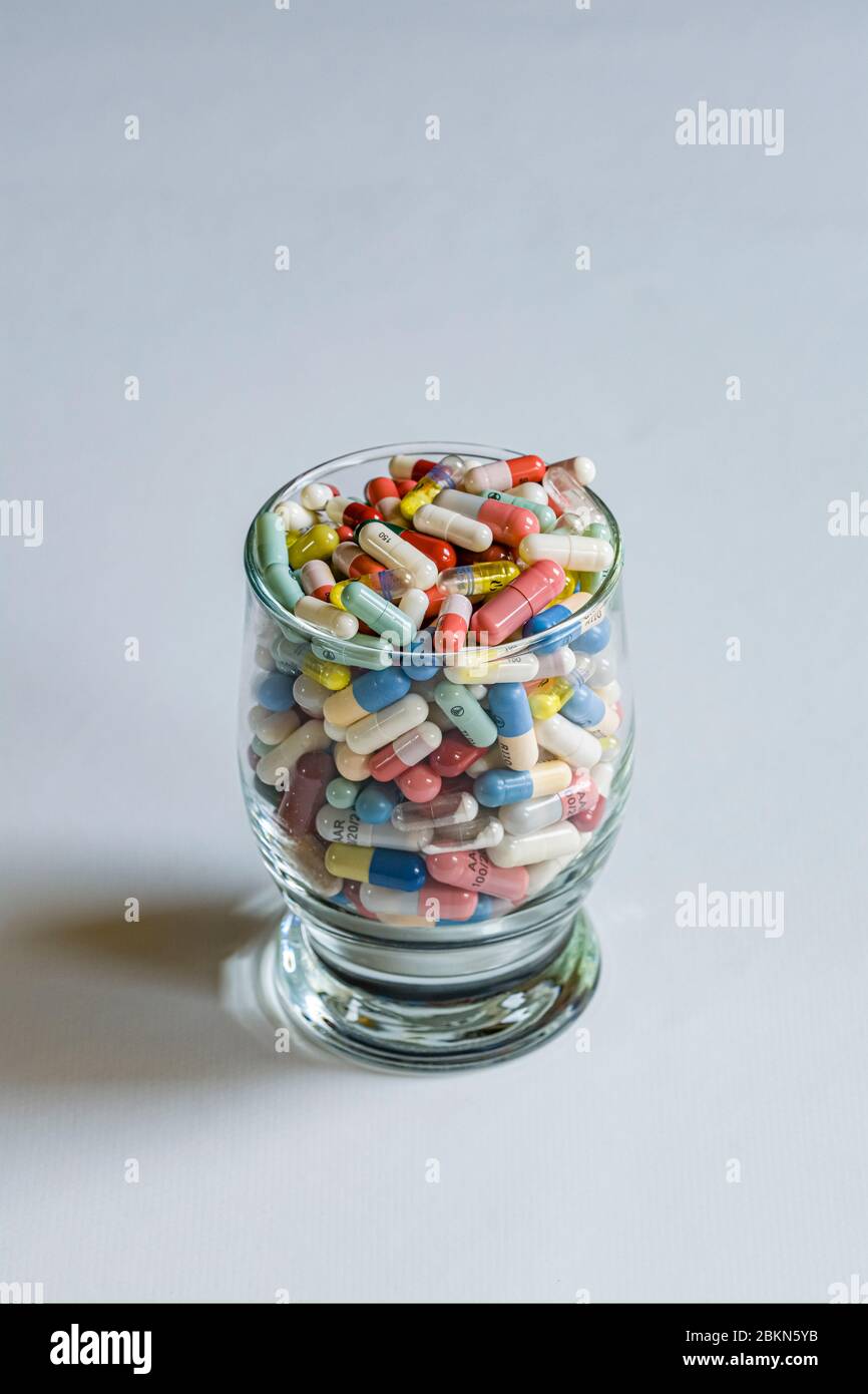 A cocktail glass filled with differently colored medical capsules ...