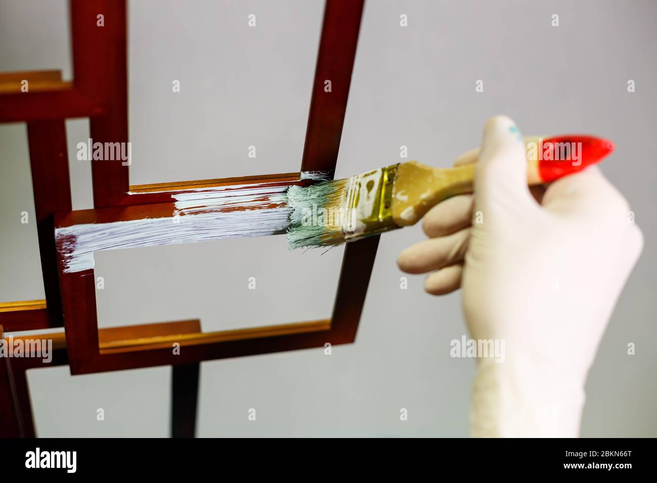 the master paints with a brush a wooden brown photo frame with light ...