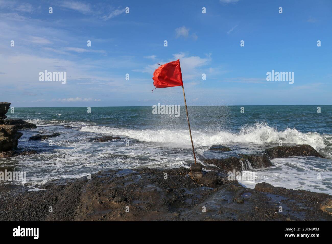 Red flag on a wooden flagpole flies on coast of Indian Ocean. Sign ...