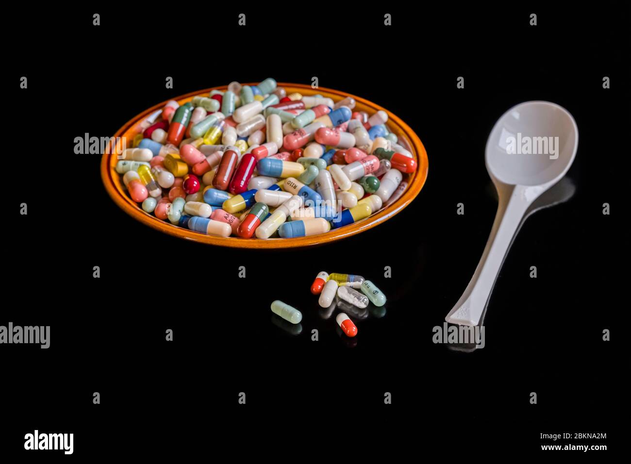 A small plate filled with differently colored medical capsules, some ...