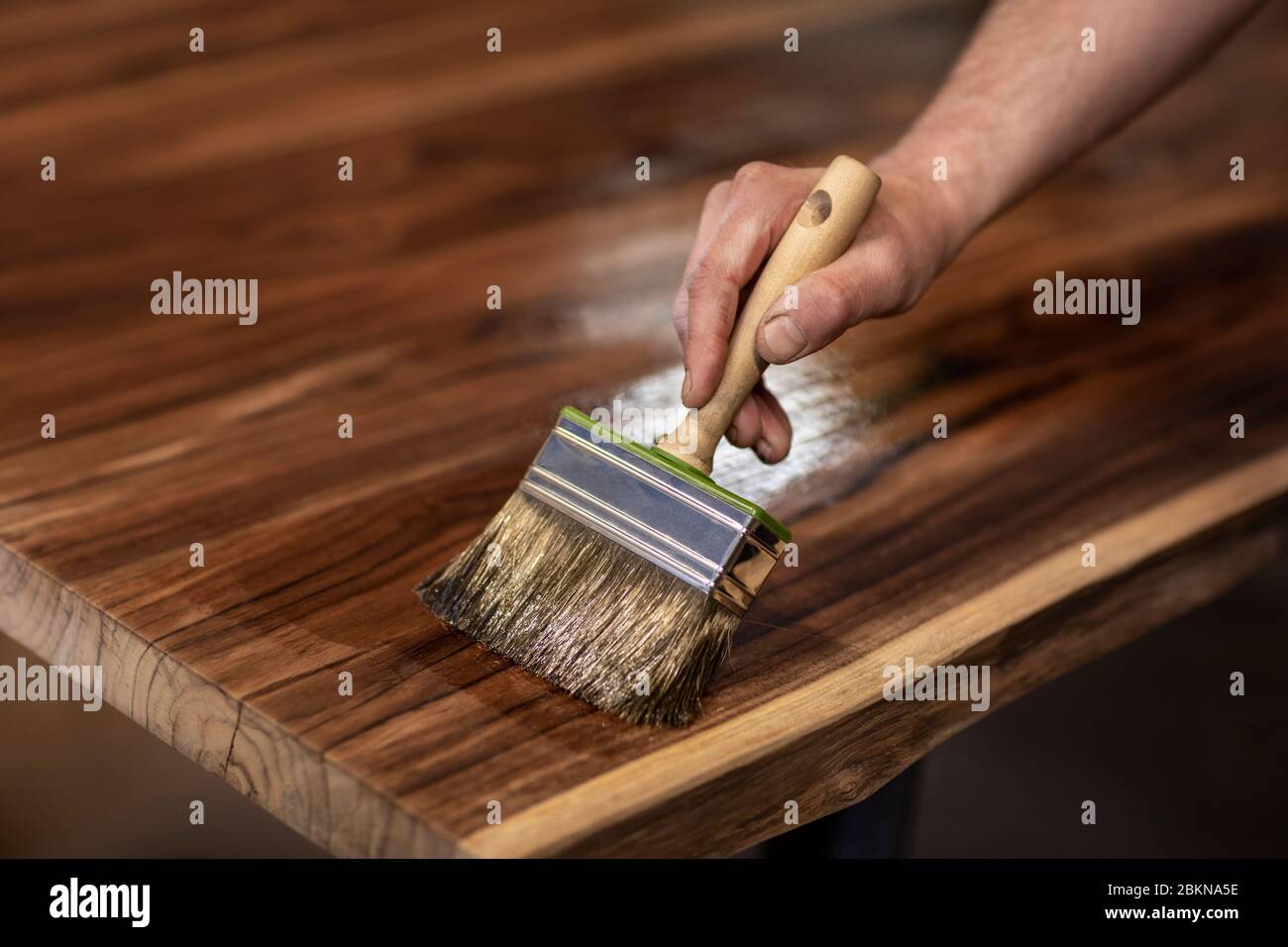 Hand of a carpenter designer oiling an authentic self made table with a ...