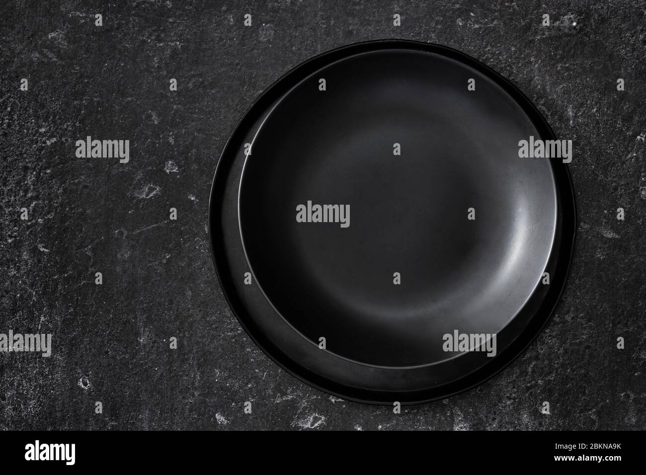 Top view of empty black plates on black background Stock Photo - Alamy