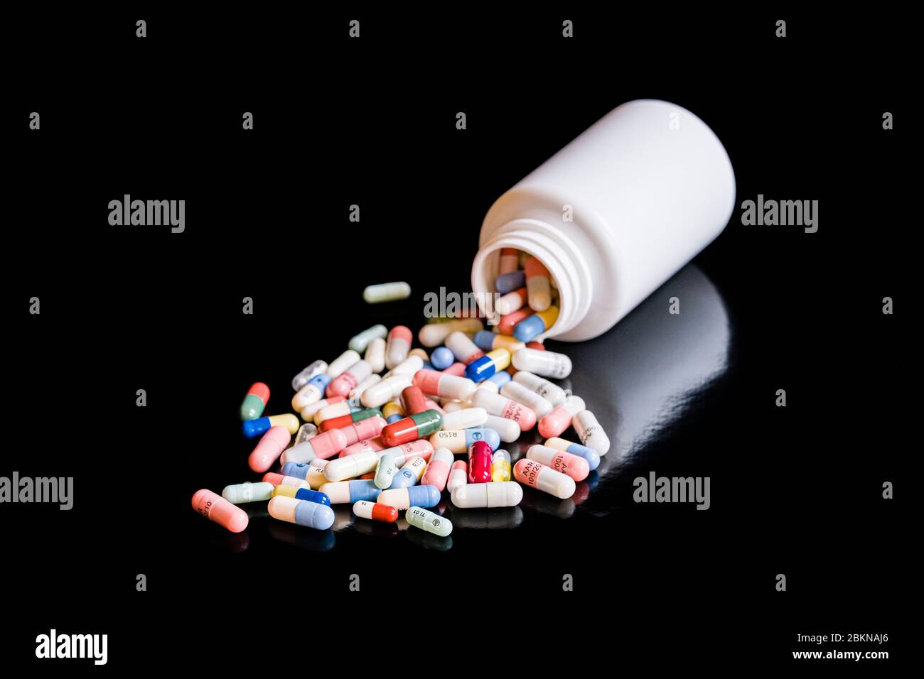 Many differently colored medical capsules, running out of a white ...