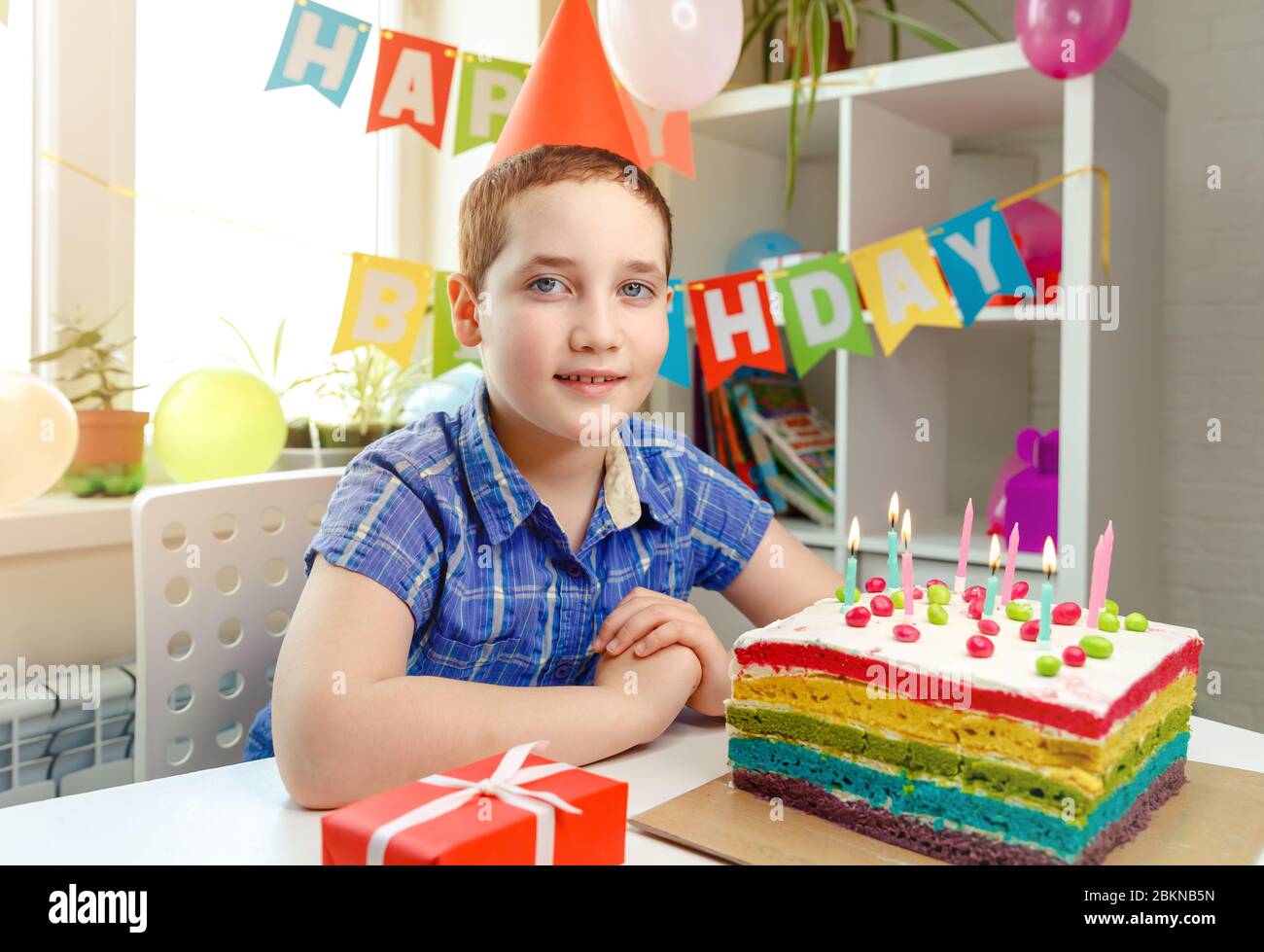 Happy child smiling in birthday cap. Birthday cake with candles. Party ...