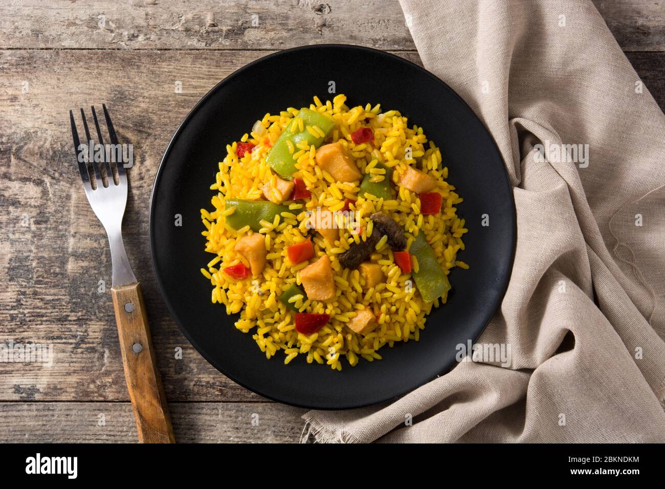 Fried rice with chicken and vegetables on black plate on wooden table ...