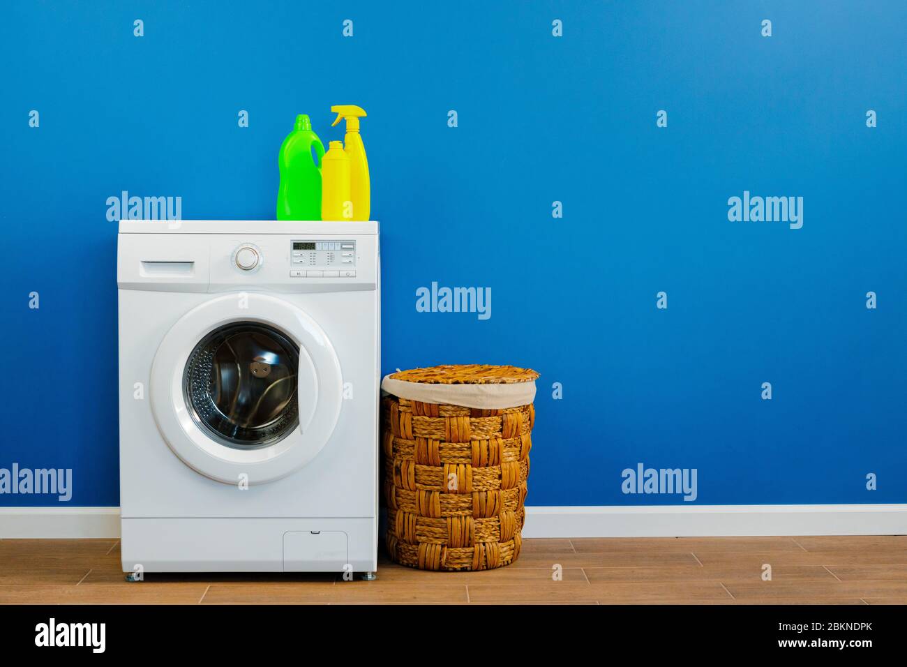 Washing machine with laundry on blue wall background Stock Photo - Alamy