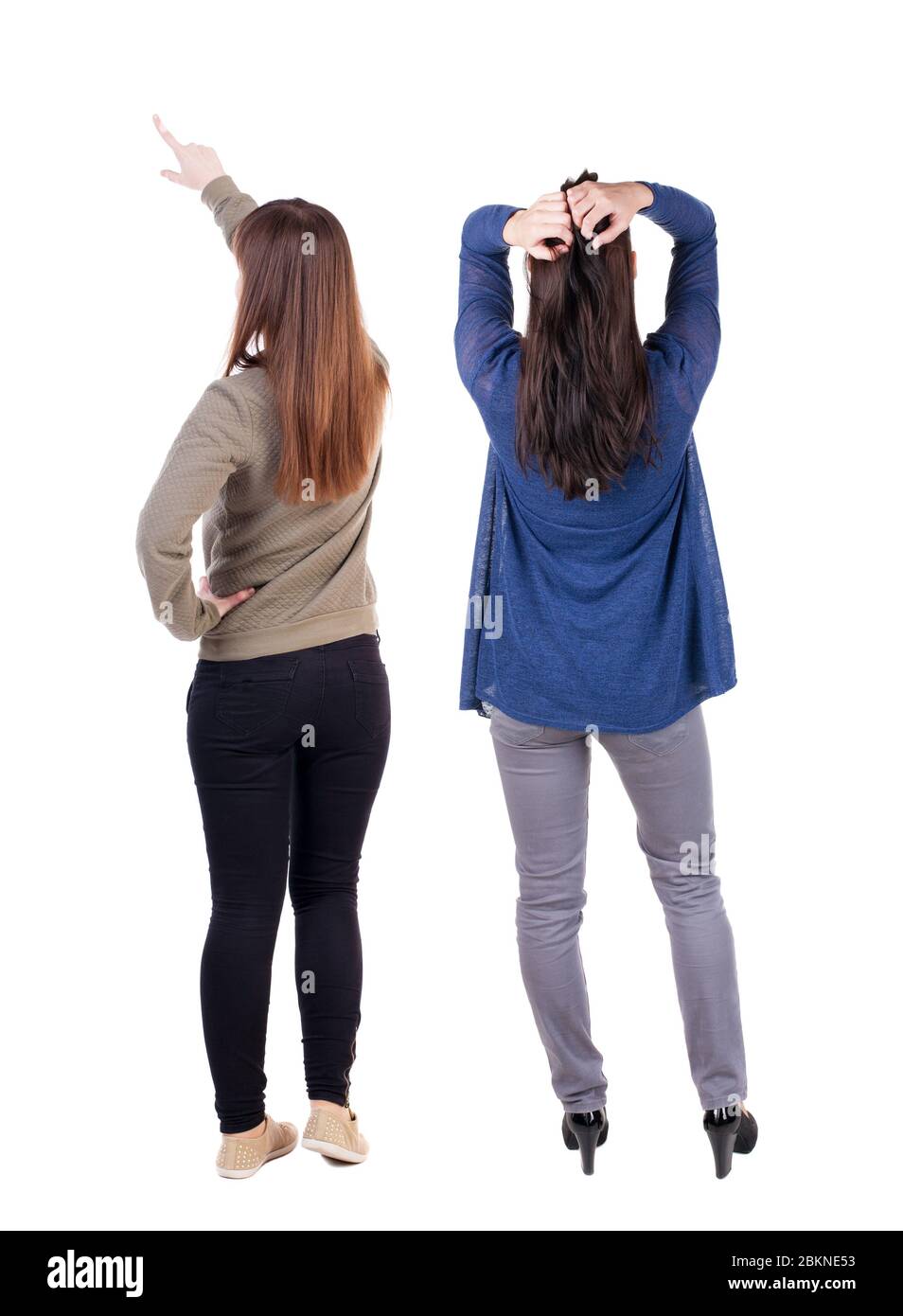 Back view of two pointing girl in sweater. Rear view people collection ...