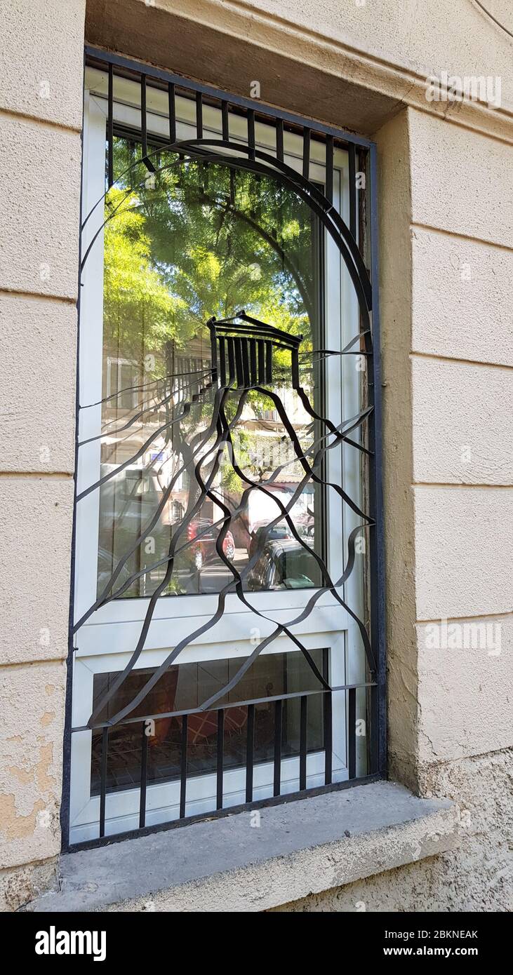 Unusual metal grating protected white window with blurry reflection in ...