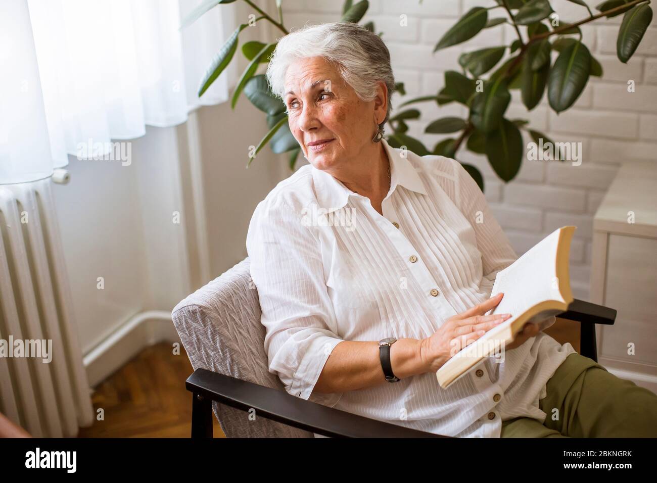 Senior woman reading a paper book in the room at home Stock Photo - Alamy