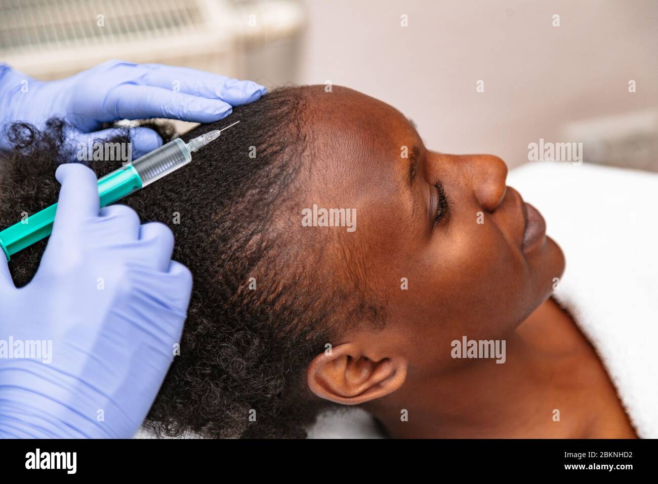 Doctor aesthetician makes head beauty injections to a female african ...