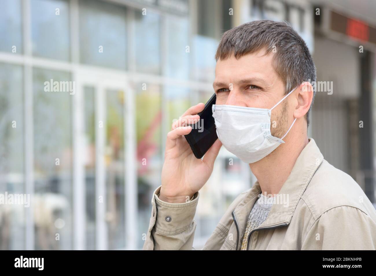 Portrait of a masked man with a mobile phone in the background of the ...
