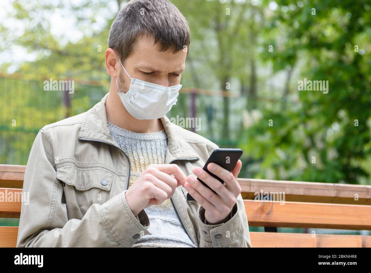 A man on a walk looks at the screen of a mobile phone Stock Photo - Alamy