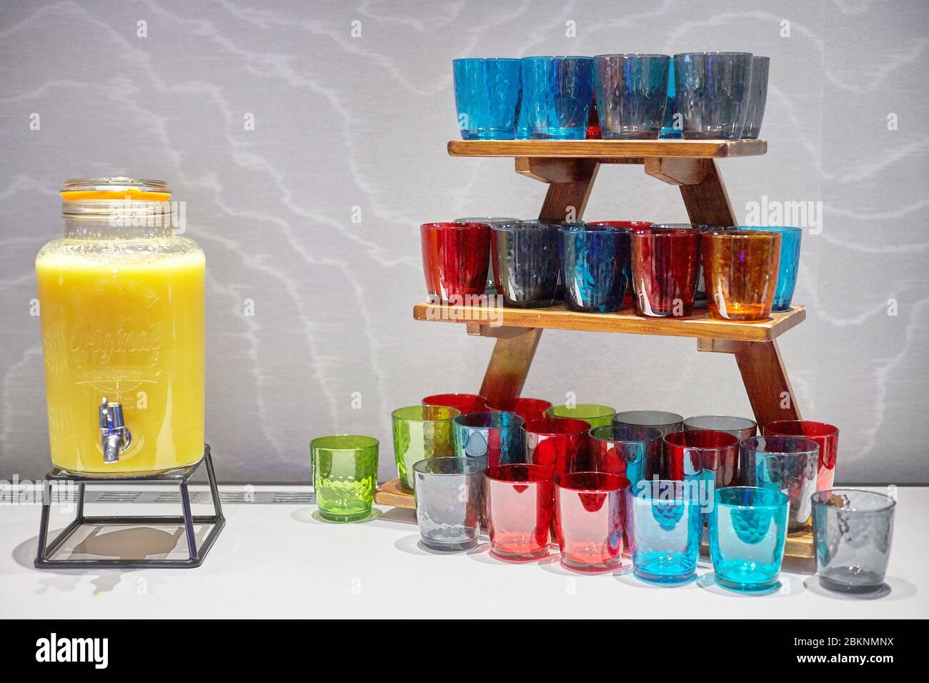 Container with citrus juice and empty multi-colored glasses Stock Photo ...