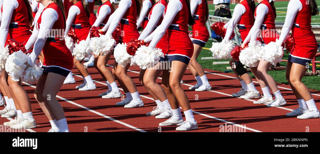 High school cheerleaders in red and white uniforms performing for the ...
