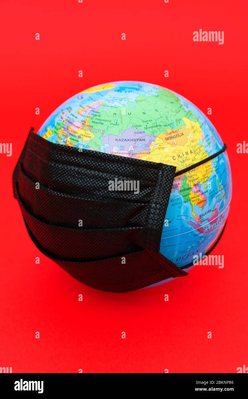 Terrestrial globe model with black surgical mask isolated on red ...