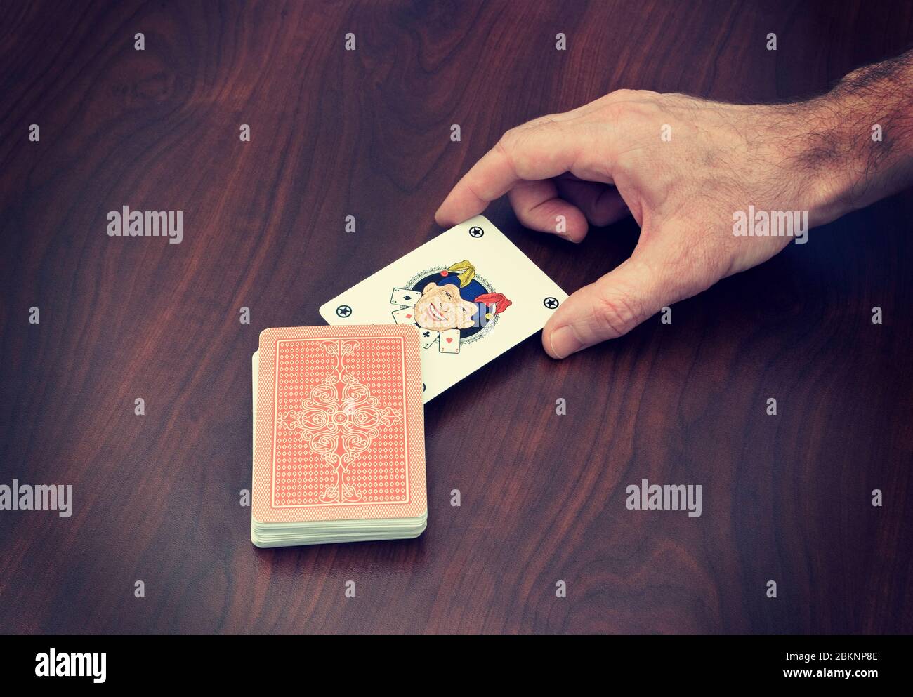 hand picking up a joker in pack of playing cards Stock Photo - Alamy