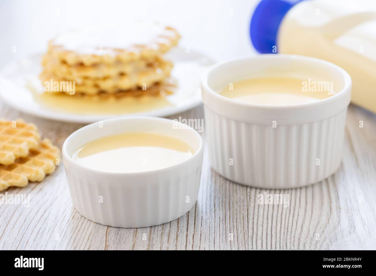 Condensed milk and waffles on a table. Sweet dessert Stock Photo - Alamy