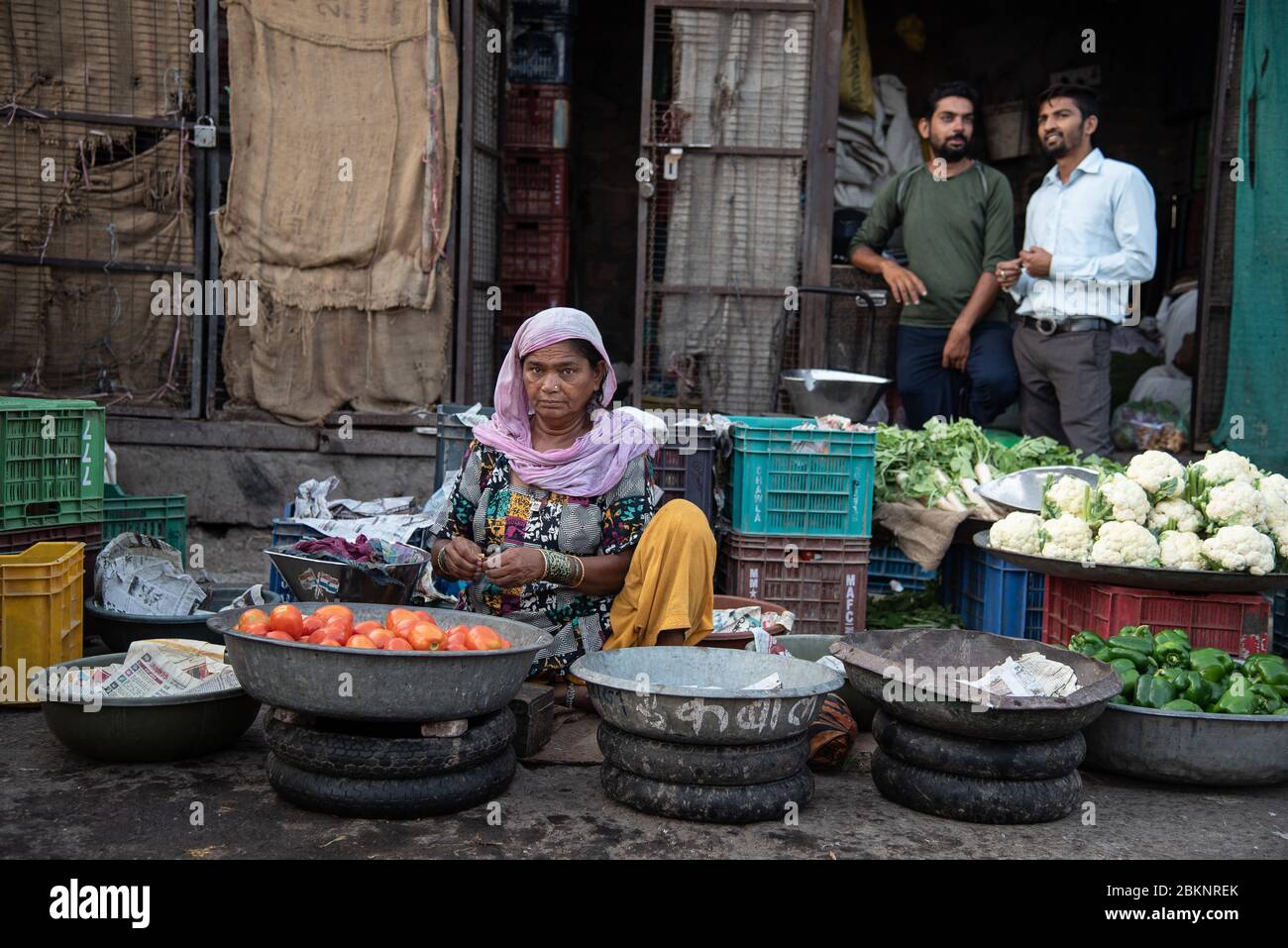 Indian female trader seated in front of her produce at the vegetable ...