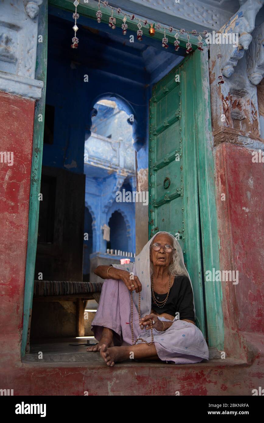 Old Indian lady with very poor eyesight sits in the doorway of her ...