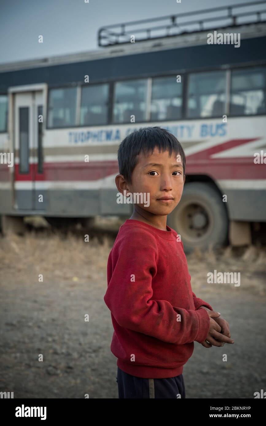 Portrait of young Indian boy in front of local community bus. Tuophema ...