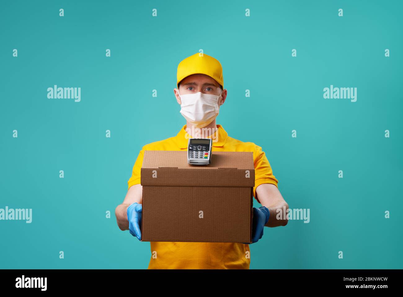 Courier with medical mask on his face holds box and pin pad. Concept of ...
