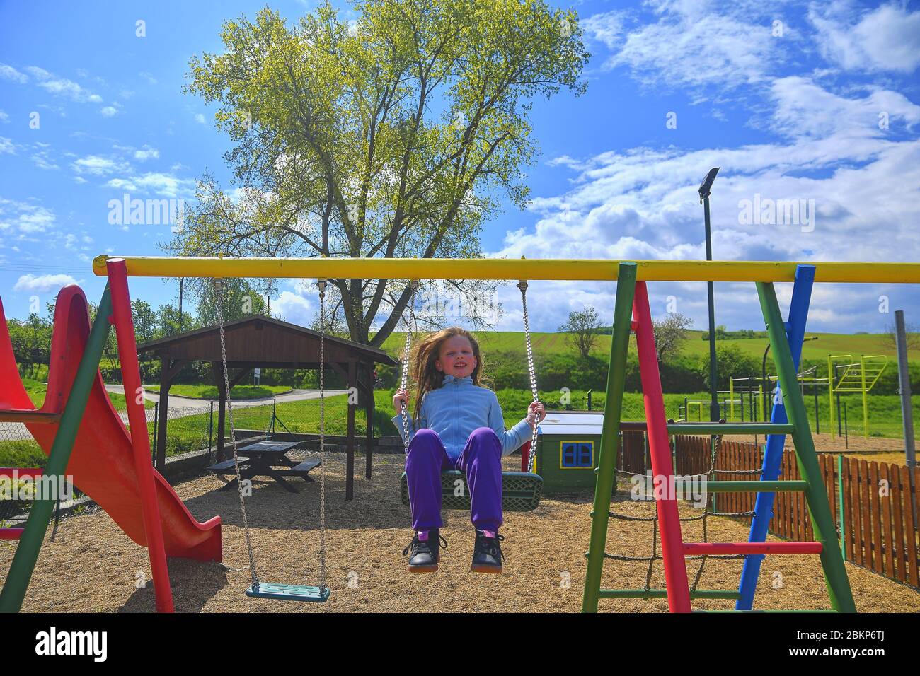 Child swinging on playground on sunny summer day in a playground. Kids ...