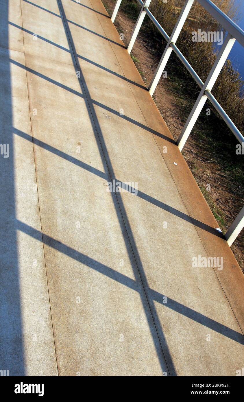 The abstract pattern of the shadows of the bridge railing on the ...