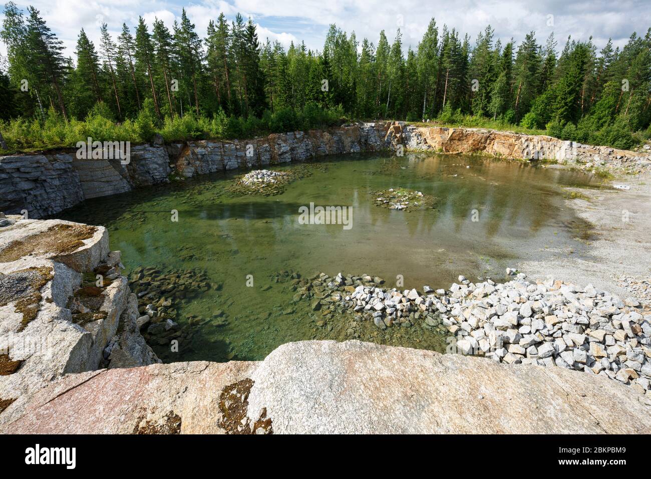 View of a small rock quarry site , bottom filled with rain and ground ...