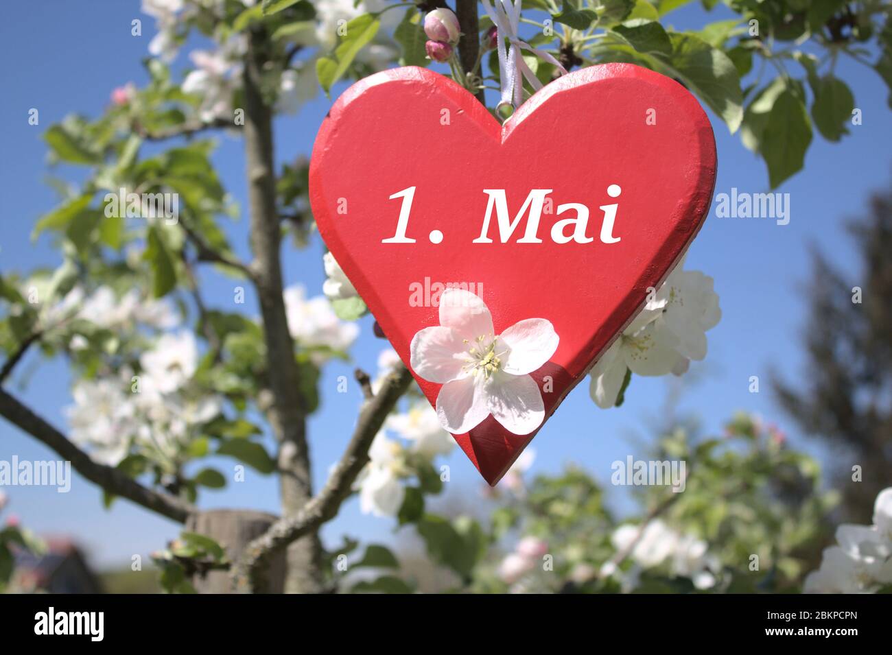 The picture shows may day decoration with a red wooden heart and the ...