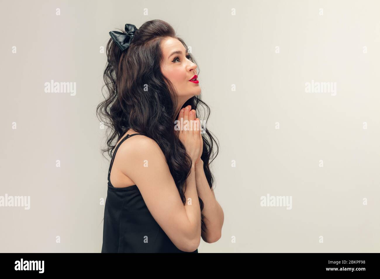 Praying, asking. Portrait of beautiful young woman on grey studio ...