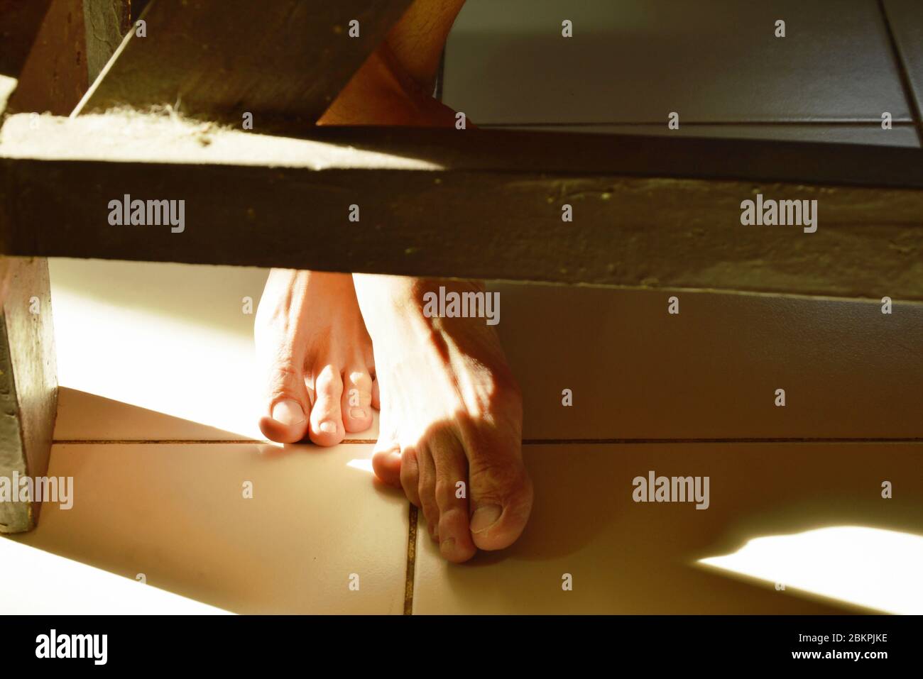 foot and leg on tile floor under wooden table in home Stock Photo - Alamy