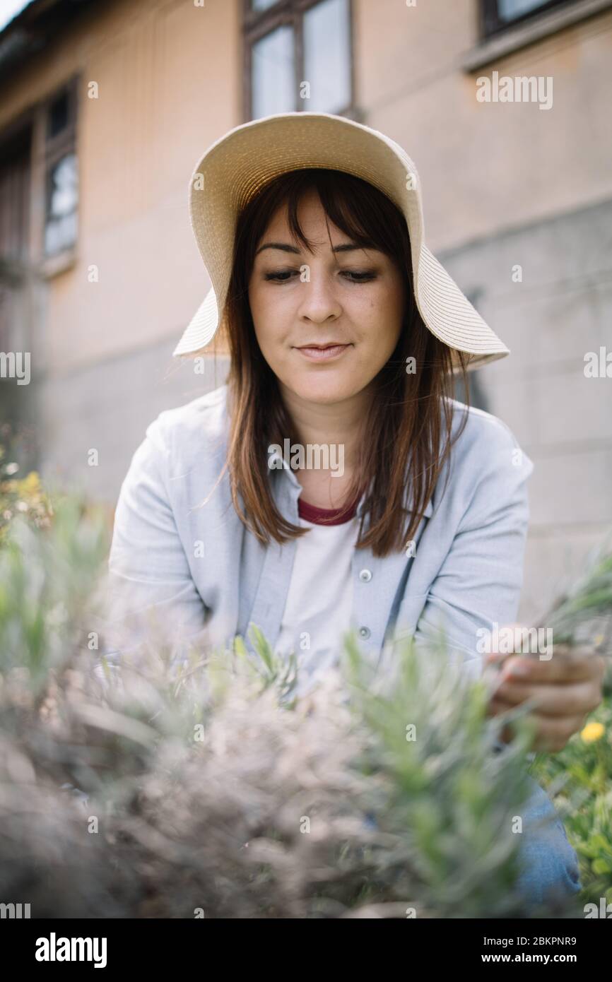 Girl sitting in yard and blurred plants. Woman squatting in garden in ...