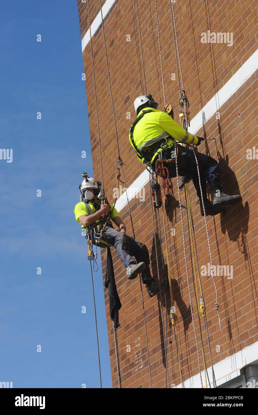Men working at height on ropes. Industrial rope access workers on the ... Men working at height on ropes. Industrial rope access workers on the ...