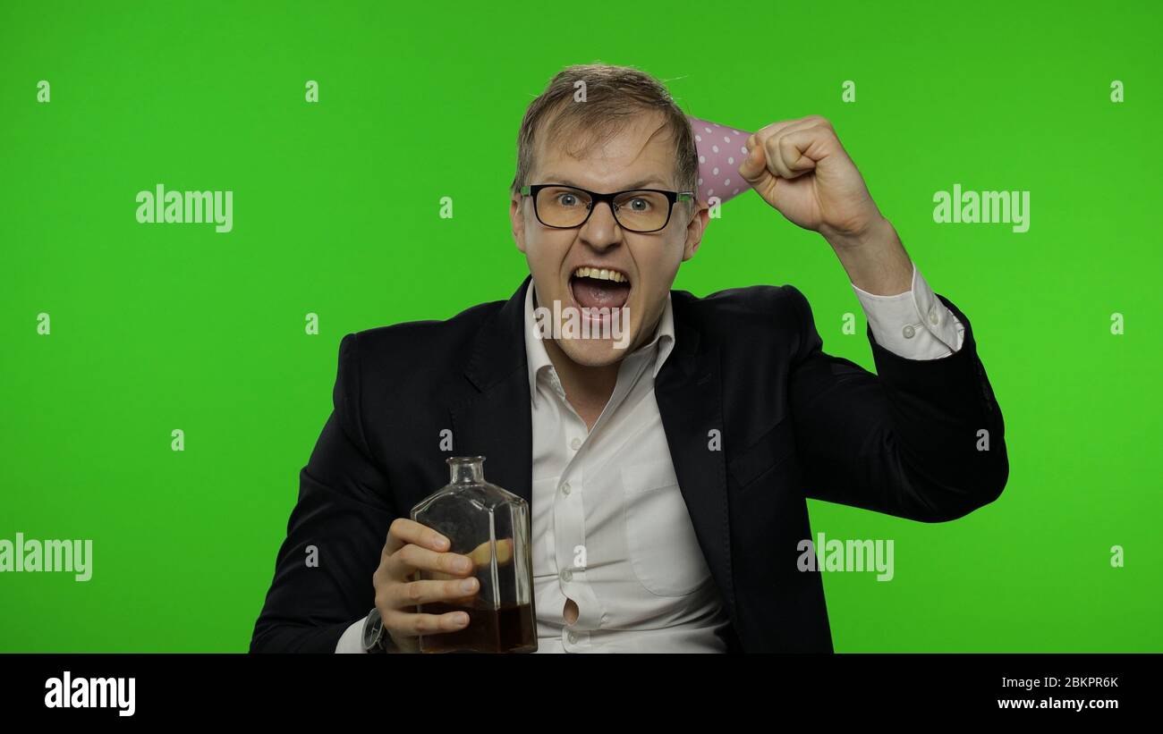 Portrait of drunk young manager celebrates, dances with alcohol bottle ...