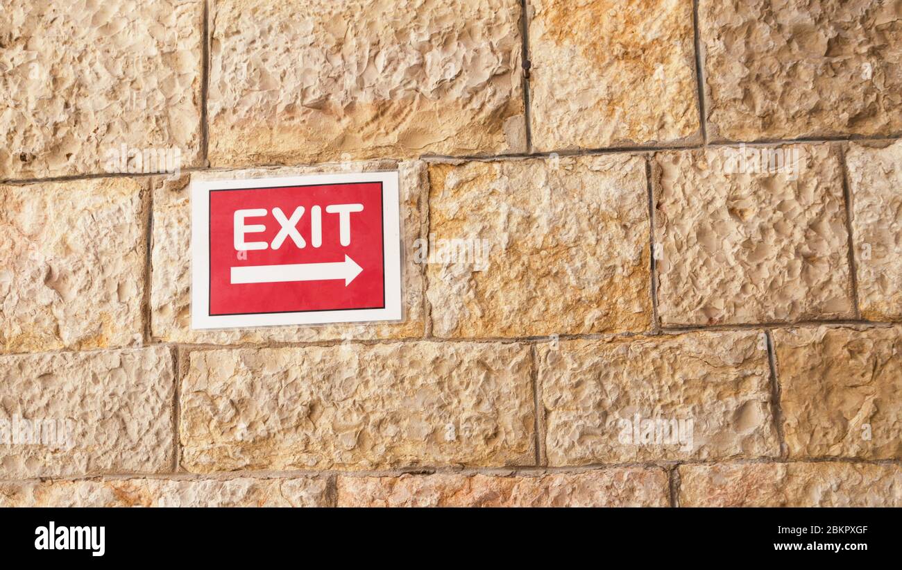 Red exit sign on sandstone textured wall 16:9 background Stock Photo ...