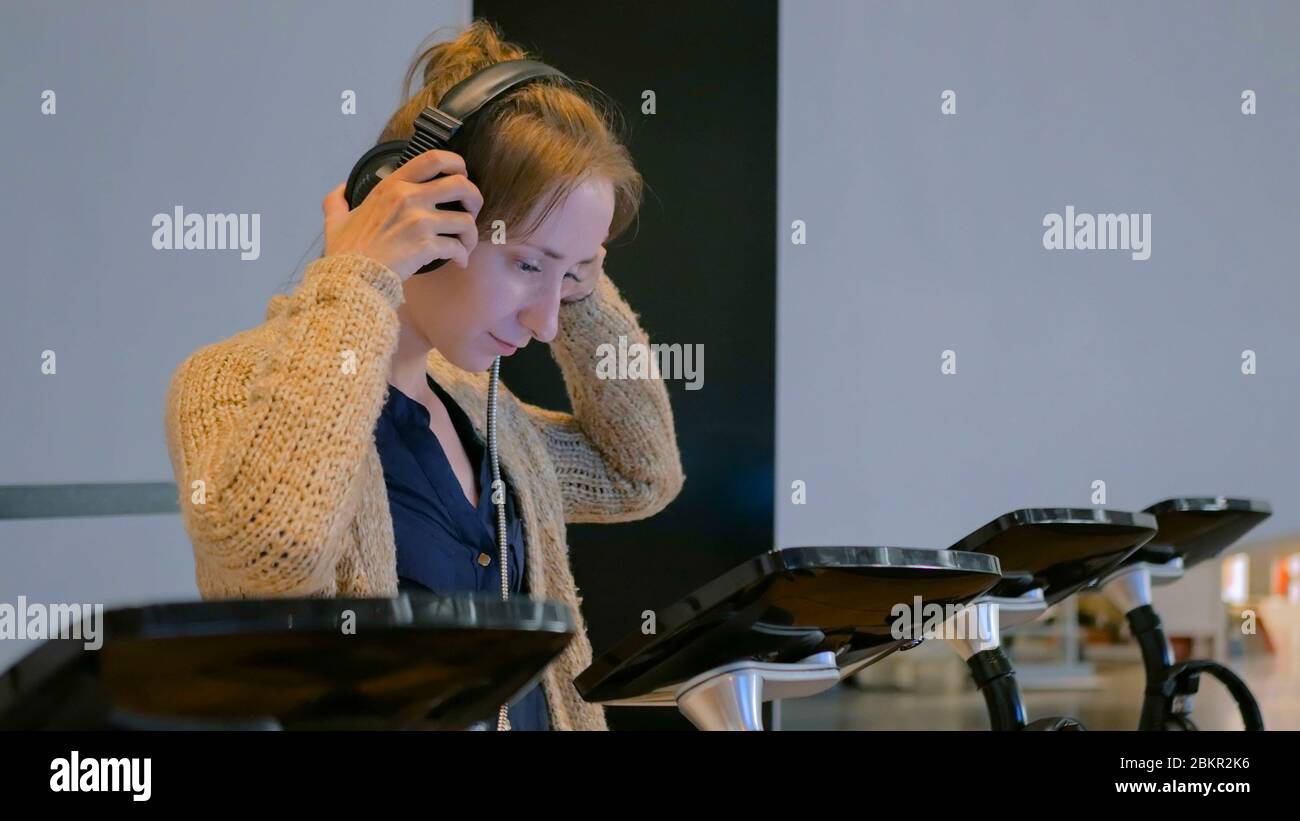 Woman using interactive touchscreen display and listening audio guide ...