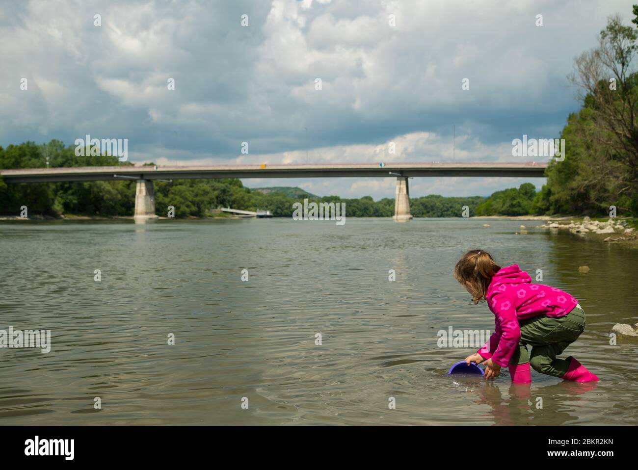 Balanced young girl kid playing on the natural river bank. Gets ...