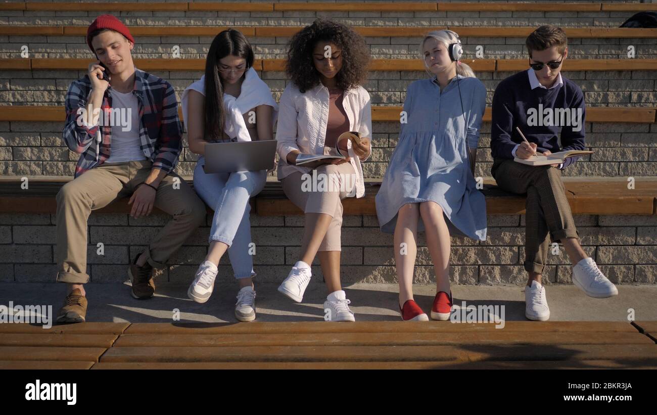Multiethnic Group of Friends sitting outside, everyone is doing Stock ...