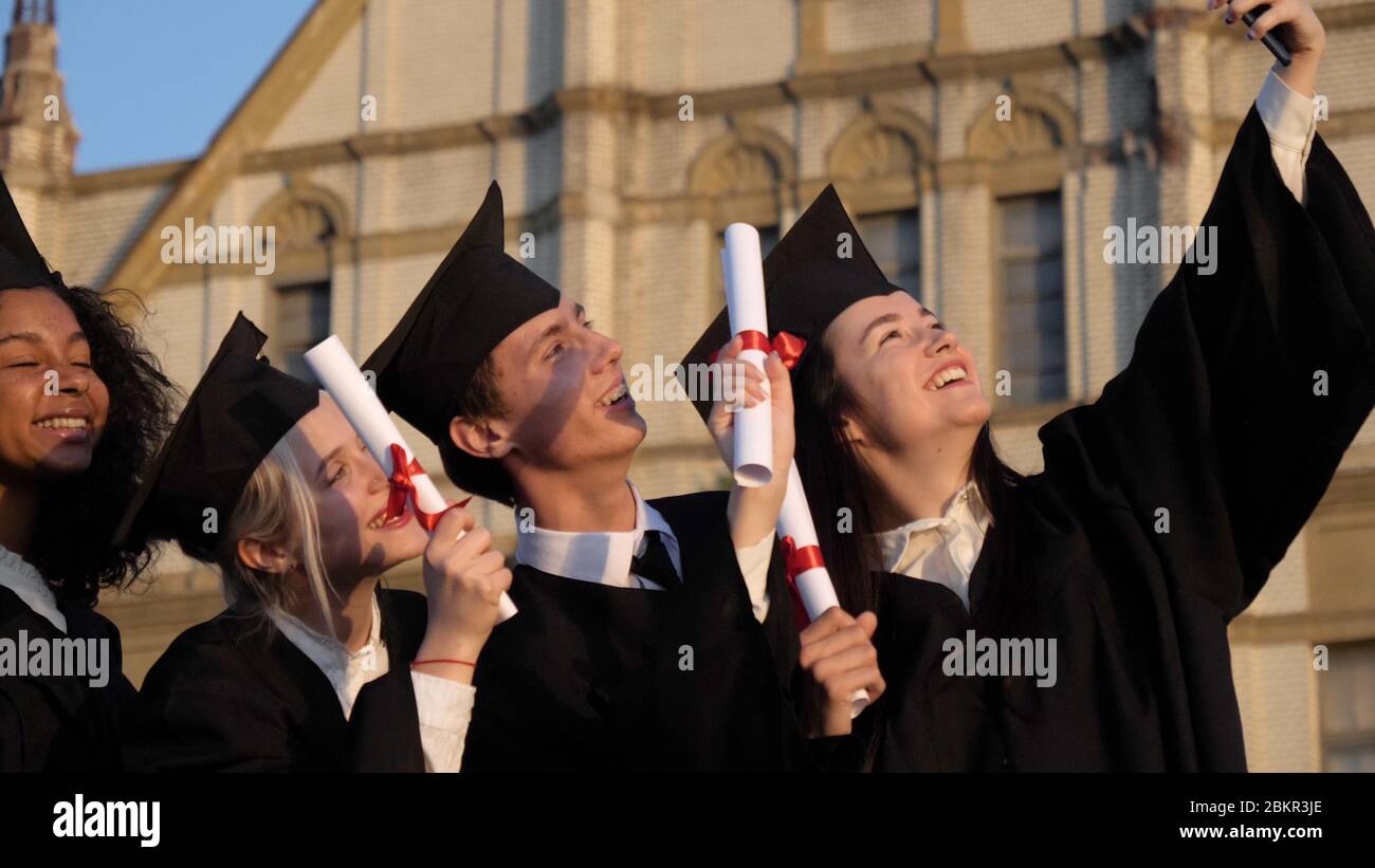 Mixed races graduated friends in black traditional gowns and cap Stock ...